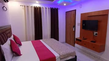 Quarto de hotel com cama, cortinas, televisão e ventoinha no teto.