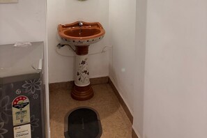 Casa de banho com lavatório de apoio, sanita e chuveiro.