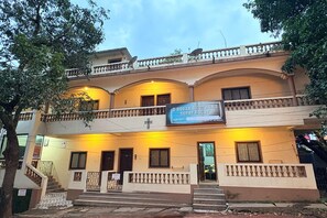 Um edifício de vários andares com uma placa indicando 'D'Souza Brothers Guest House', sinalizando um estabelecimento de hospedagem.