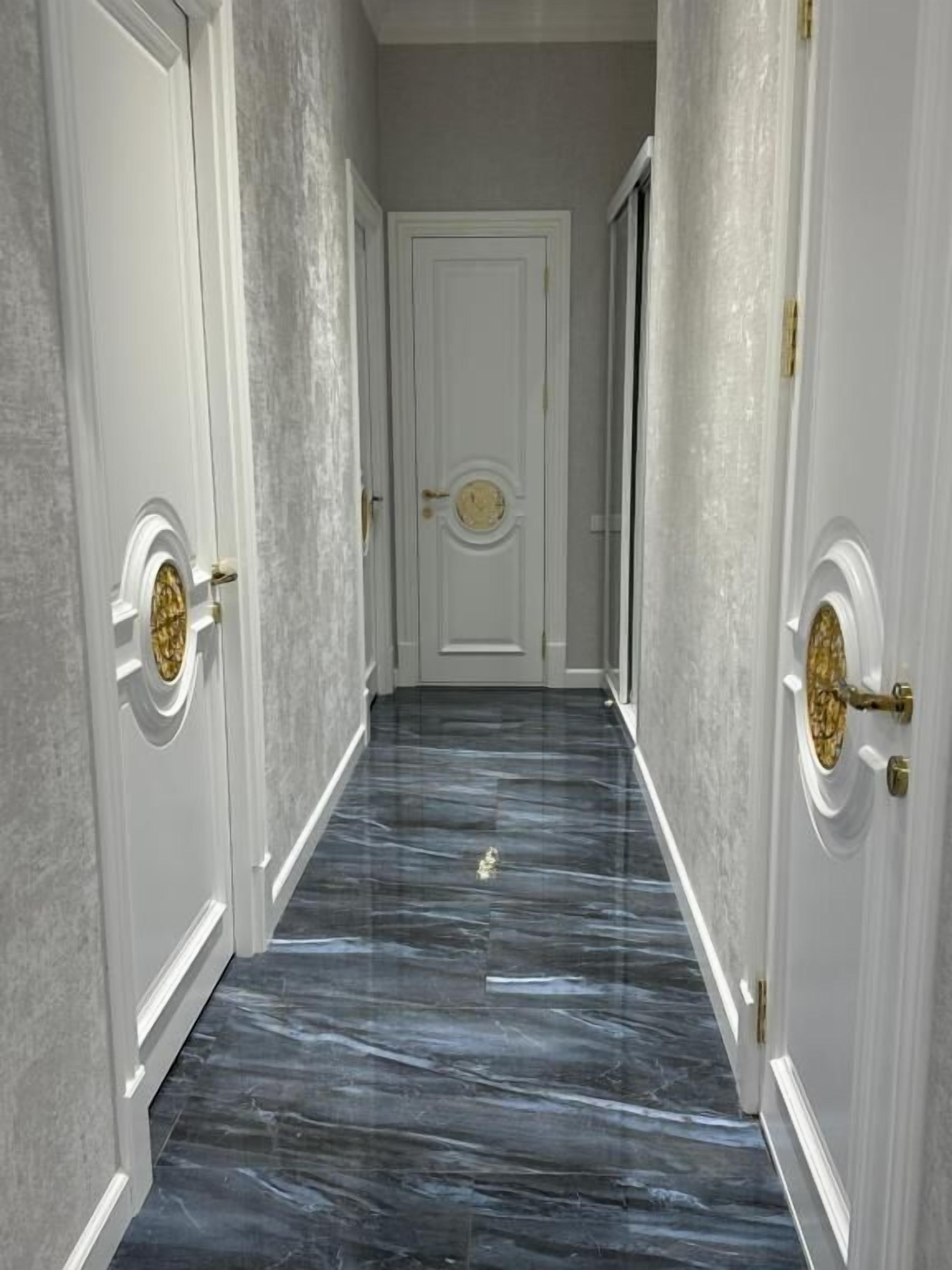 Corredor com portas brancas e piso de mármore.