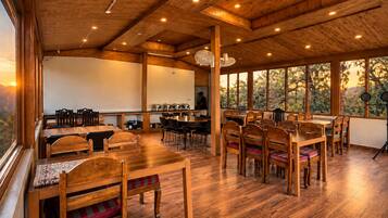 Ampla sala de jantar com mobiliário de madeira e grandes janelas com vista para o exterior.