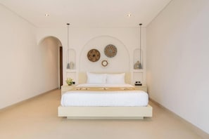 Quarto minimalista com uma cama no centro, acompanhada por mesas de cabeceira com abajures.