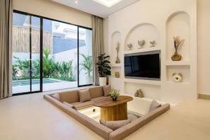 Uma sala de estar moderna com um sofá grande, uma mesa de centro e uma televisão presa à parede.
