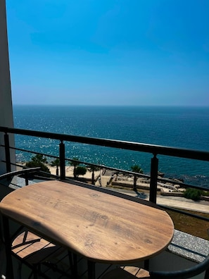 Varanda com mesa de madeira e vista para o mar.