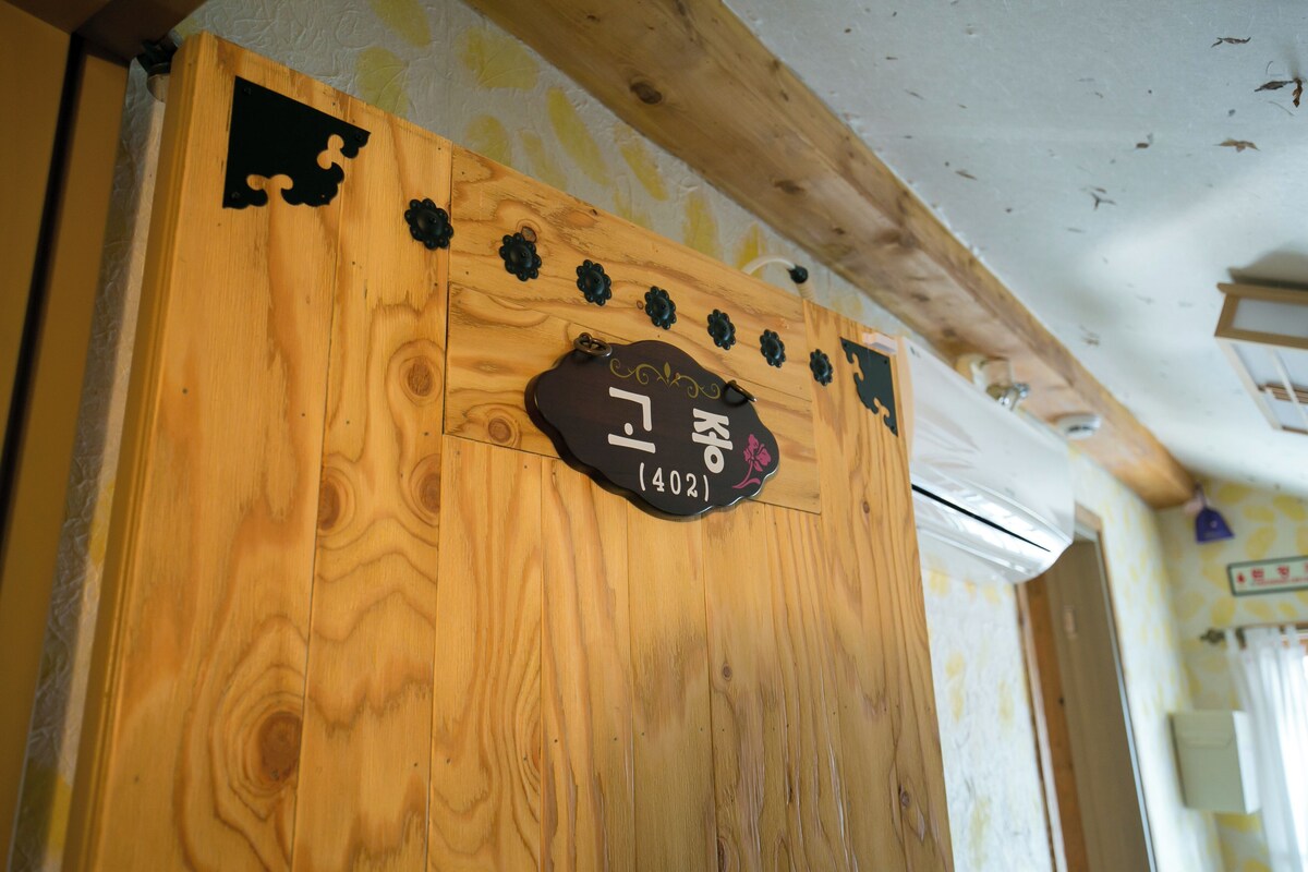 Uma porta de madeira com uma placa preta que diz 'Kofuku 1402'.