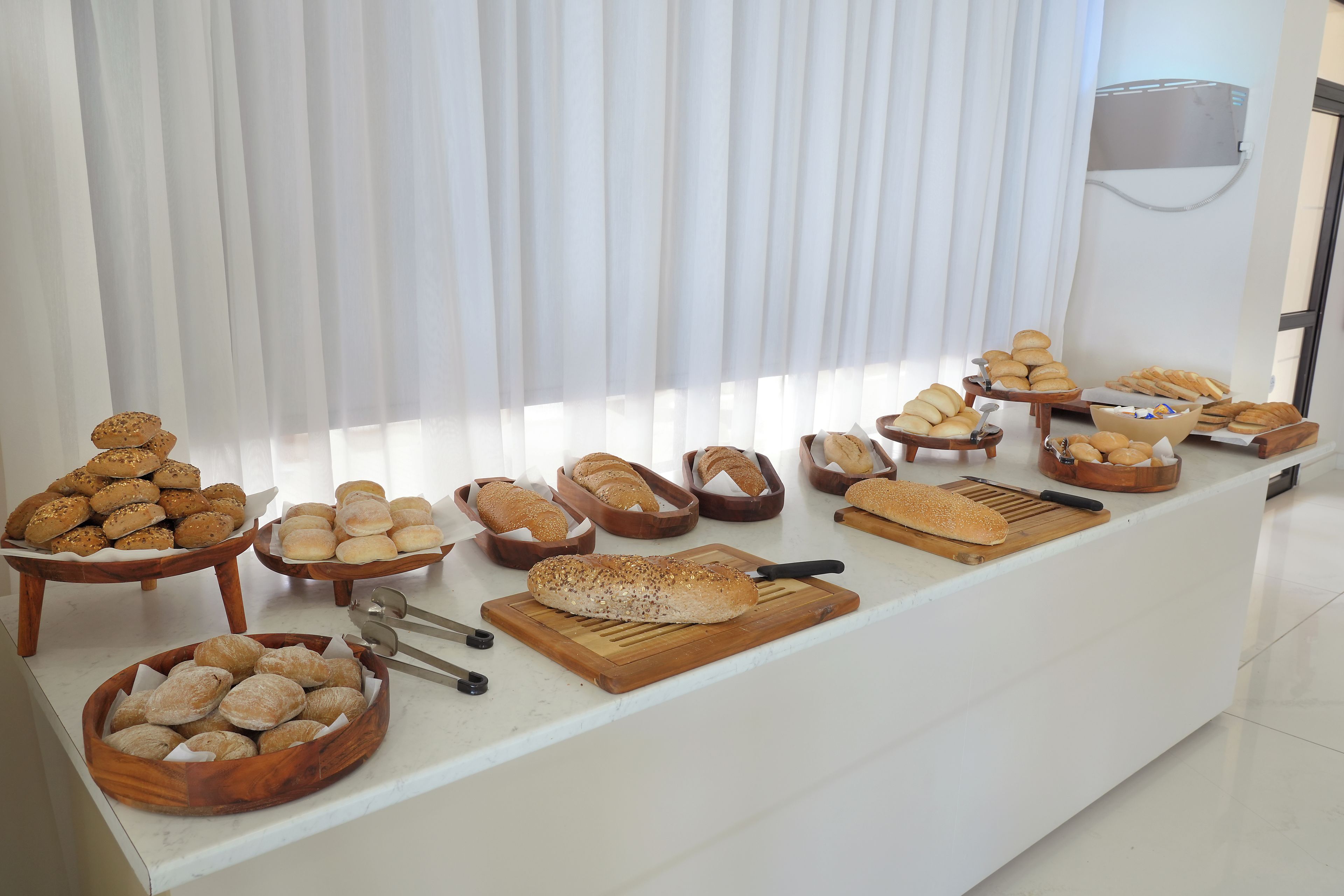 Mesa de buffet com diversos tipos de pão e doces.