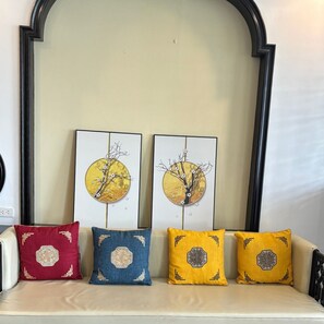 Um sofá com quatro almofadas em vermelho, azul e amarelo, cada uma com um desenho circular e um emblema central.