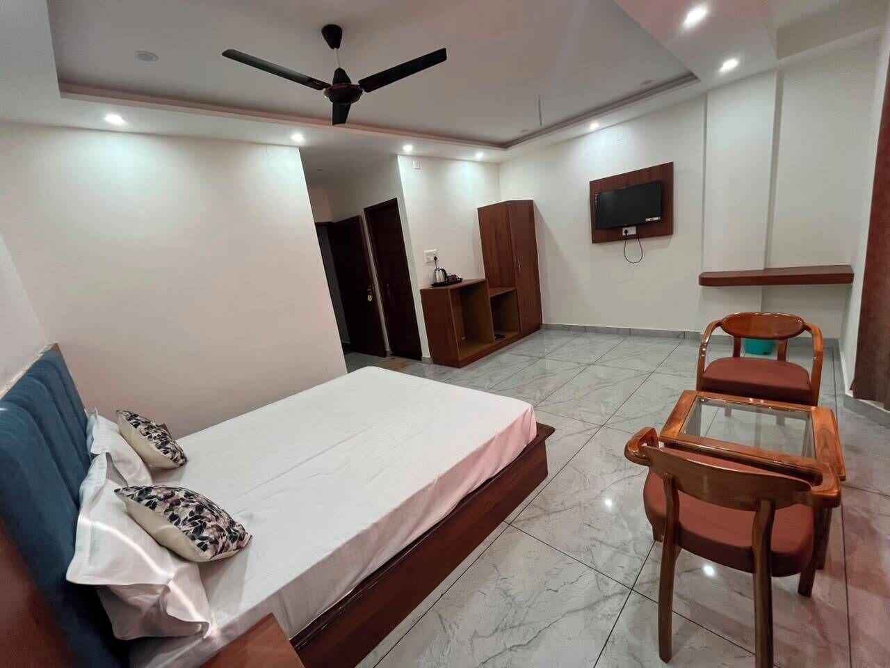 Um quarto com uma cama, uma cadeira, uma televisão e um guarda-roupa.