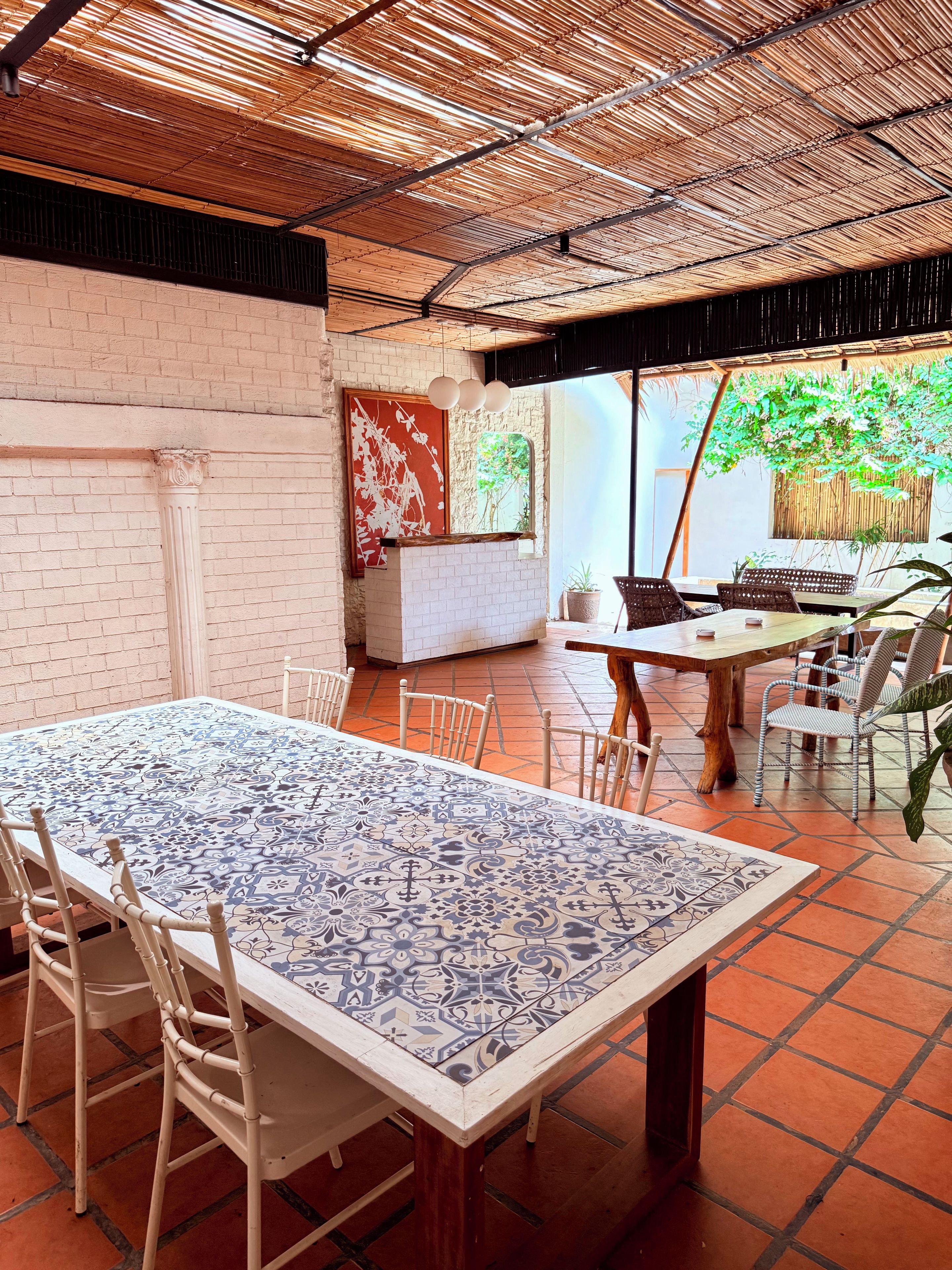 Espaço de refeições com uma mesa grande, cadeiras e vista para um jardim.