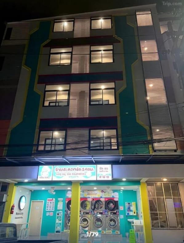 Edifício de vários andares com lavanderia no andar térreo, fachada colorida e diversas janelas.