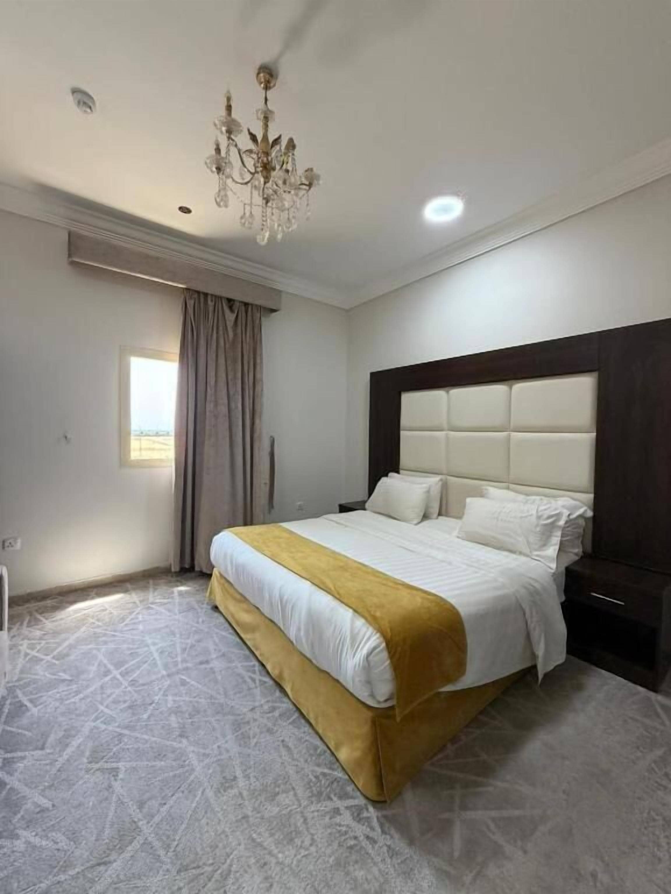 Quarto de hotel com uma cama grande, um lustre e vista para o exterior.