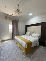 Quarto de hotel com uma cama grande, um lustre e vista para o exterior.