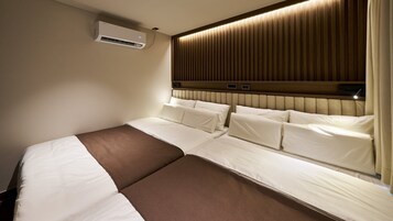 Quarto de hotel com uma cama, ar-condicionado fixado na parede e cabeceira de madeira.