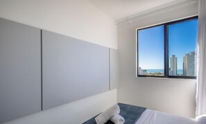 Quarto de hotel com uma cama, janela com vista para a cidade e um guarda-roupa espaçoso.