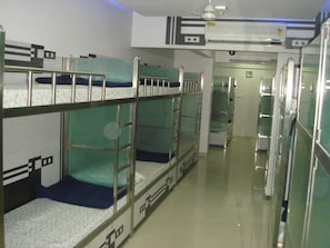 Um corredor com beliches, um ventilador de teto e um aparelho de ar condicionado.