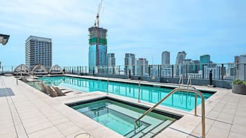 Piscina no terraço com paisagem urbana ao fundo, incluindo um prédio alto em construção.