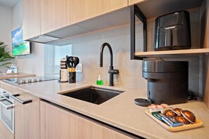 Cozinha moderna com pia embutida, máquina de café e bancada com escorredor de louça para cápsulas de café.