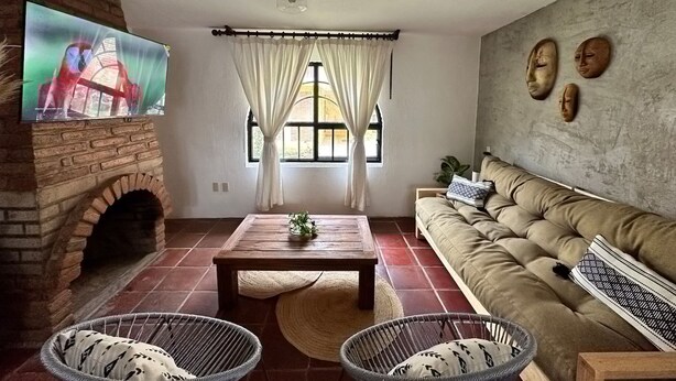 Uma sala de estar com lareira de tijolos, televisão, sofá e mesa de centro.