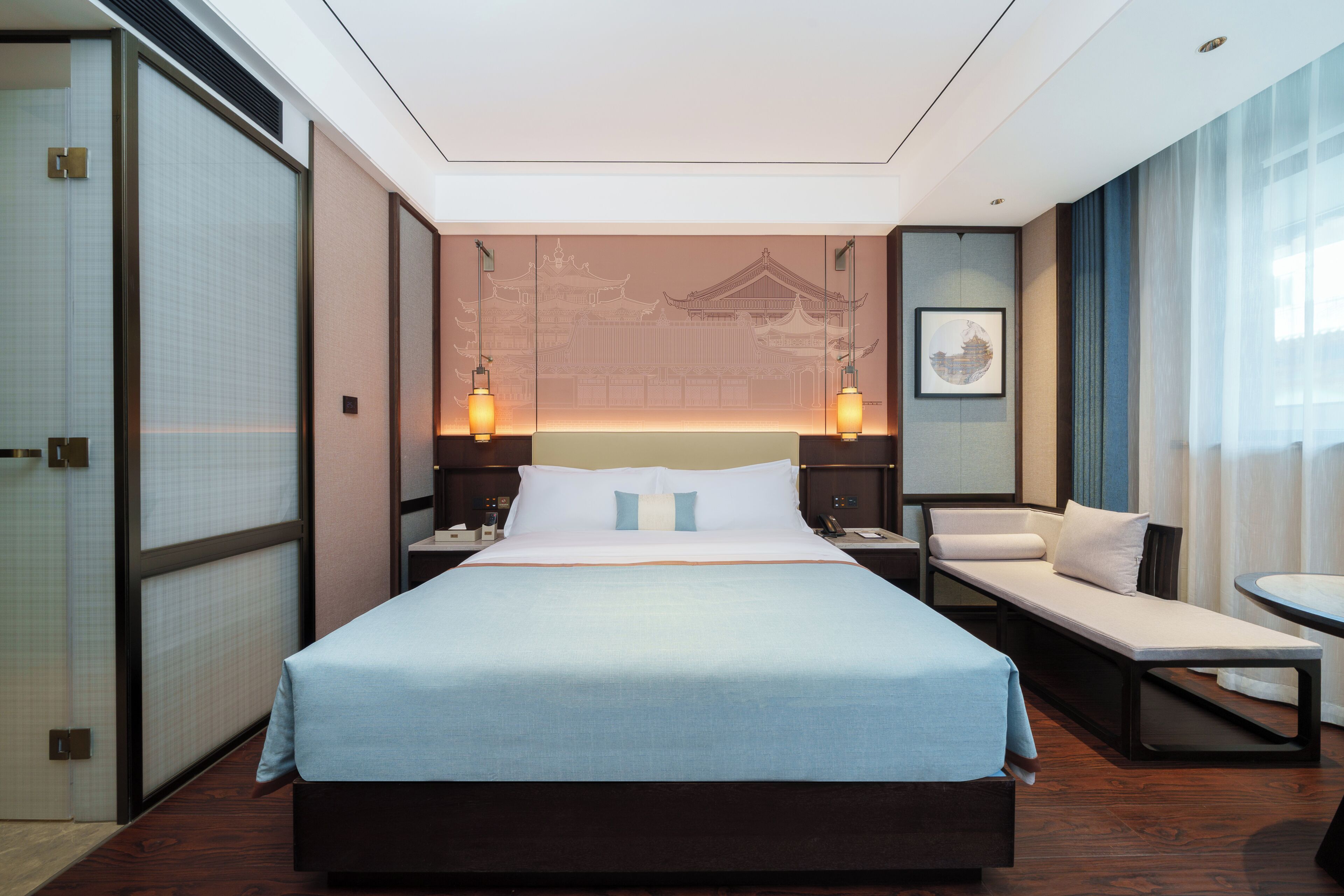 Quarto de hotel com uma cama grande, mesas de cabeceira, escrivaninha, cadeira e vista para um edifício tradicional.