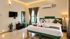 Quarto de hotel com cama, mesa de cabeceira, televisão, aparelho de ar condicionado e um vaso de plantas.
