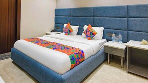 Quarto de hotel com cama, mesa de cabeceira, ventilador de teto e porta.