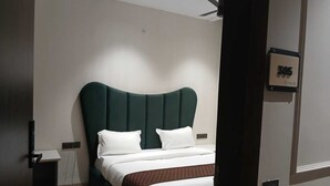Quarto de hotel moderno com uma cama grande, um ventilador de teto e uma porta com um número.
