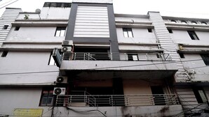Um edifício com vários andares, varandas, aparelhos de ar condicionado e uma placa indicando uma residência para hóspedes.