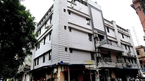 Edifício de vários andares com fachada plana, varandas e um espaço comercial no térreo com sinalização.