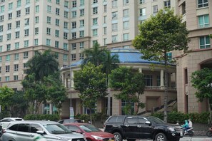 Edifício de vários andares com átrio central, cercado por carros estacionados e árvores.