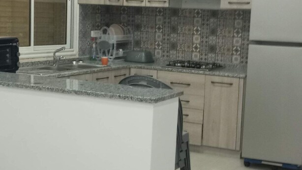 Cozinha moderna com ilha central, armários embutidos e geladeira de aço inoxidável.