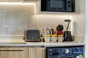 Uma cozinha equipada com micro-ondas, torradeira, liquidificador e cafeteira.