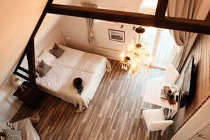 Quarto com cama, cadeira, escrivaninha, lustre e janela.