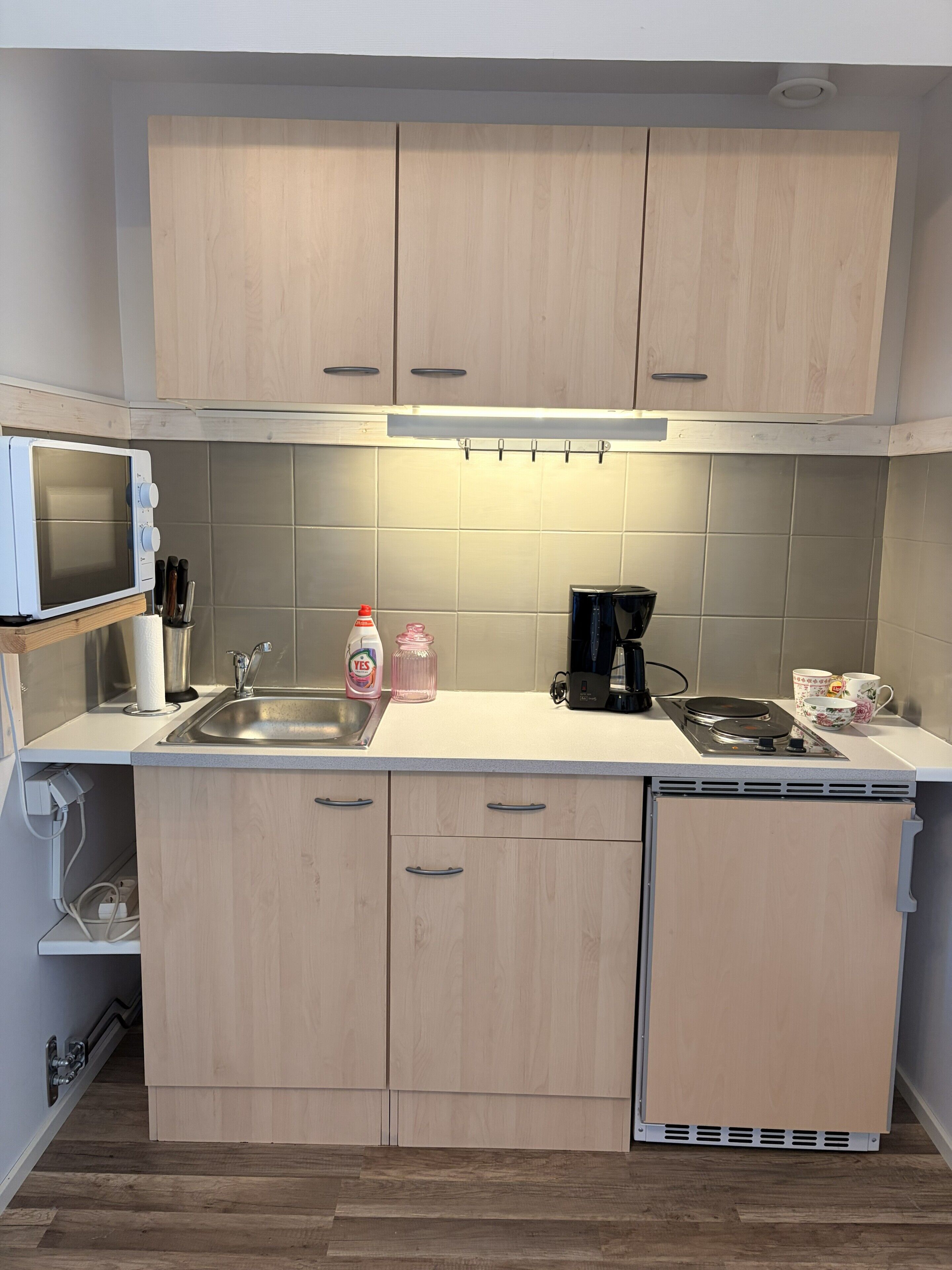 Cozinha compacta com micro-ondas, pia e cafeteira.