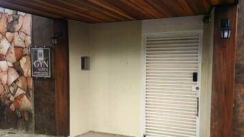 Um edifício com parede de pedra, porta de persiana fechada e placa indicando GYN SUITES.
