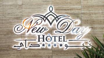 Placa de hotel com 'New Day HOTEL' e detalhes decorativos.