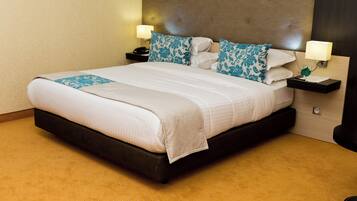 Quarto de hotel com uma cama grande, duas mesas de cabeceira e uma cabeceira.