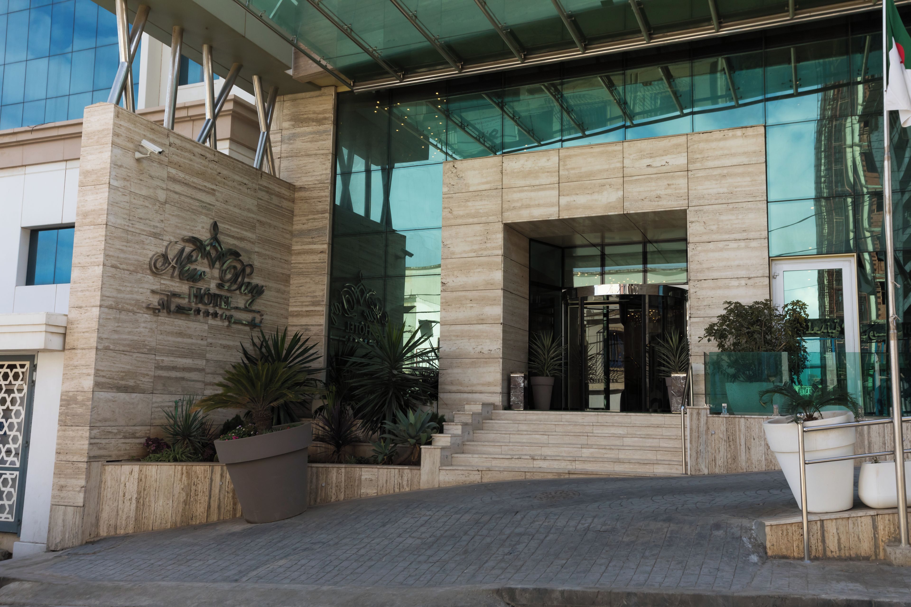Entrada de hotel com design moderno, fachada de vidro e detalhes em pedra.