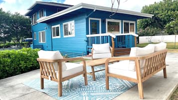 Uma casa azul com varanda, móveis de madeira e um tapete estampado.
