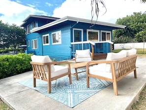 Uma casa azul com varanda, móveis de madeira e um tapete estampado.
