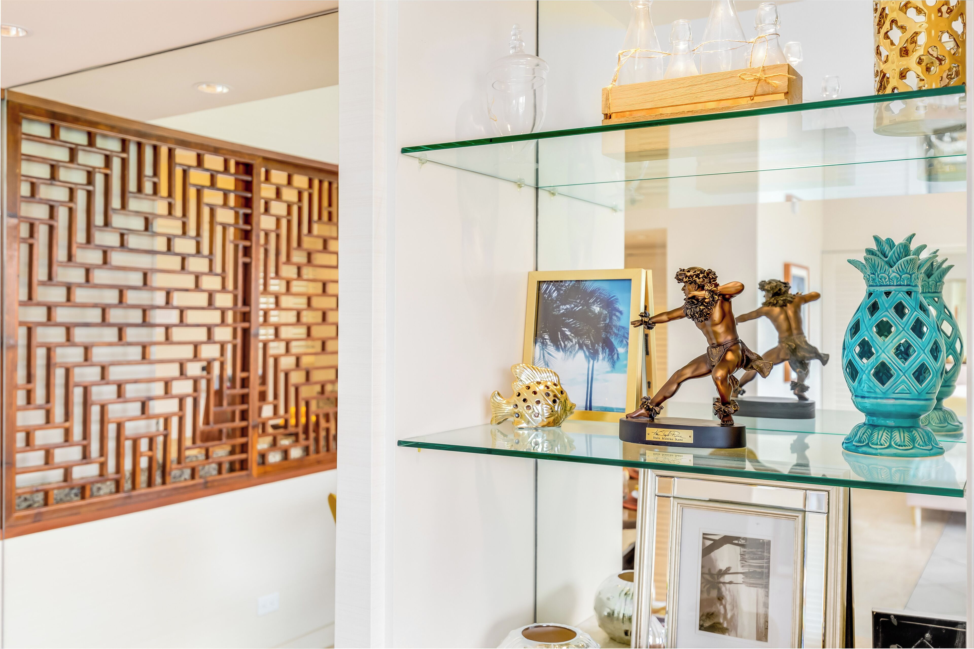 Um interior moderno com uma parede decorativa de madeira, uma prateleira de vidro com diversos objetos e um quadro emoldurado.