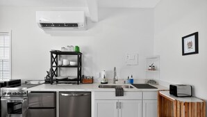 Cozinha moderna com eletrodomésticos de aço inoxidável, uma estante preta e um aparador de madeira.