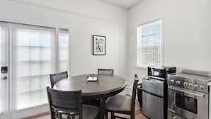 Cozinha compacta com mesa de jantar, cadeiras, fotografia emoldurada e forno embutido.