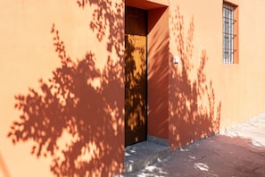 Entrada de um edifício com porta de madeira e janela com grades de metal.