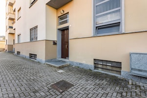 Edifício com entrada no andar térreo, porta e janela com grade de metal.