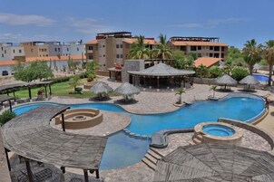 Resort com uma grande piscina, áreas de estar ao ar livre e vista dos edifícios ao redor.