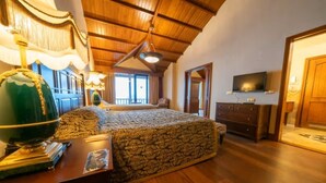 Quarto com cama grande, teto de madeira, televisão e escrivaninha com globo.