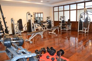 Uma academia com diversos equipamentos de exercícios, incluindo aparelhos de musculação e halteres.