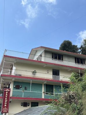Um edifício com vários andares, varandas, uma placa de identificação e uma parede verde.