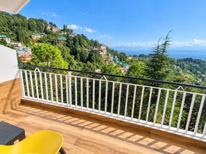 Uma varanda com guarda-corrimão branco, piso de madeira e uma cadeira amarela.