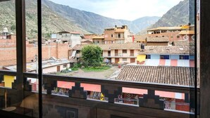 Vista de uma aldeia montanhosa com edifícios tradicionais e céu claro.